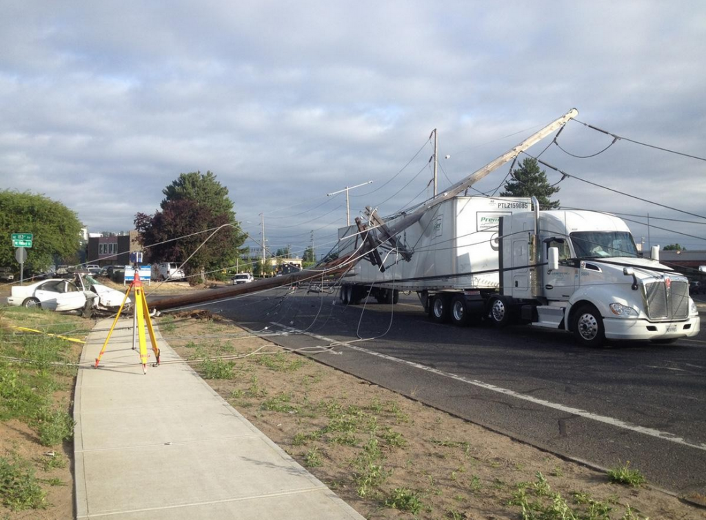 Car knocks power pole onto semi truck, trapping driver inside for hours